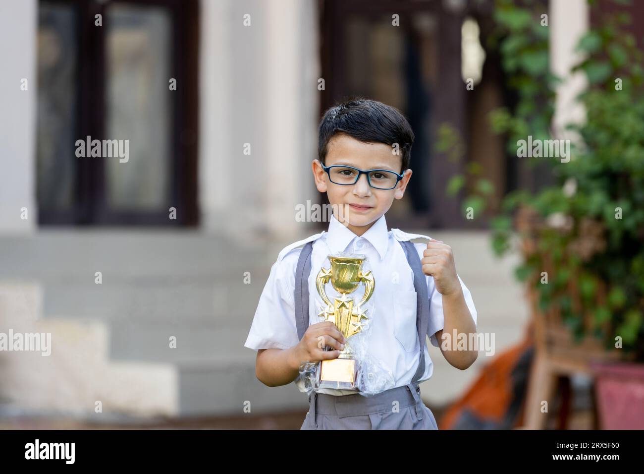 Happy Indian student schoolboy wearing school uniform holding victory ...