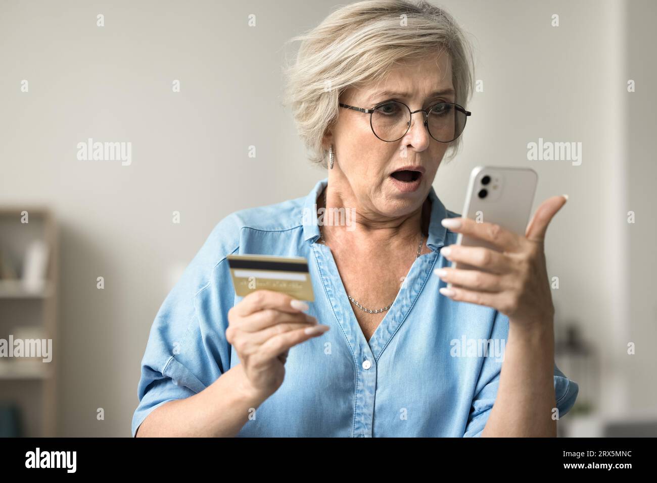 Shocked concerned mature woman in glasses holding credit card Stock ...