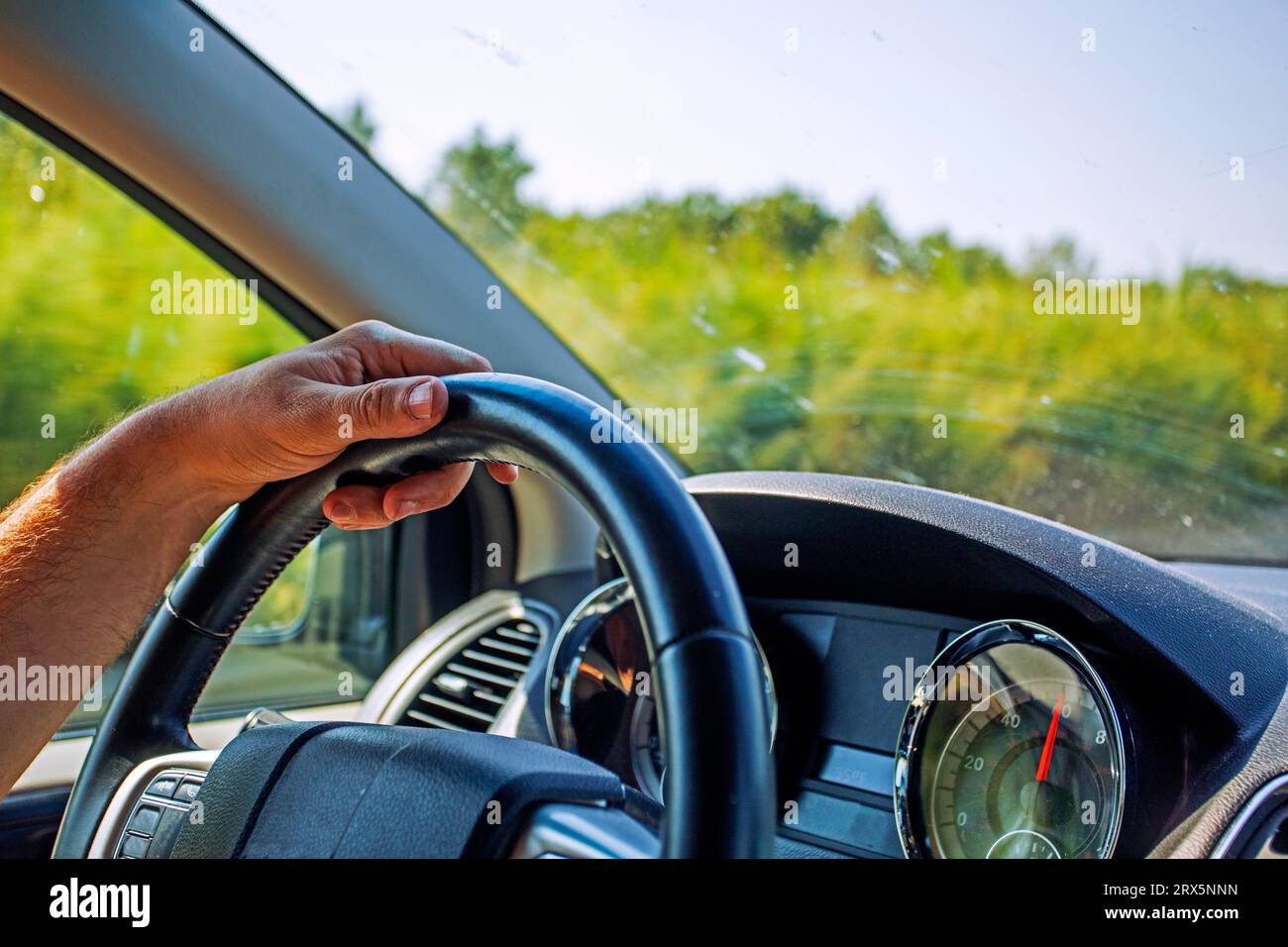 man's hand holds the steering wheel in the car while driving ...