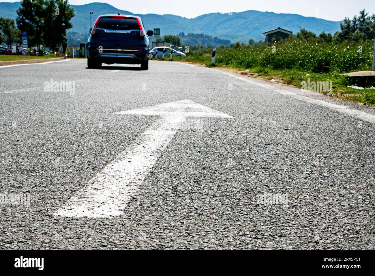 road white arrow sign on the road before gas stations and parking at ...