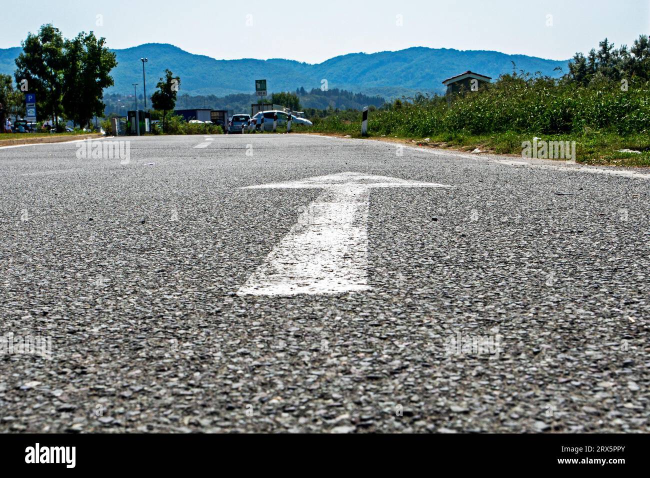 road white arrow sign on the road in the mountains before gas stations ...
