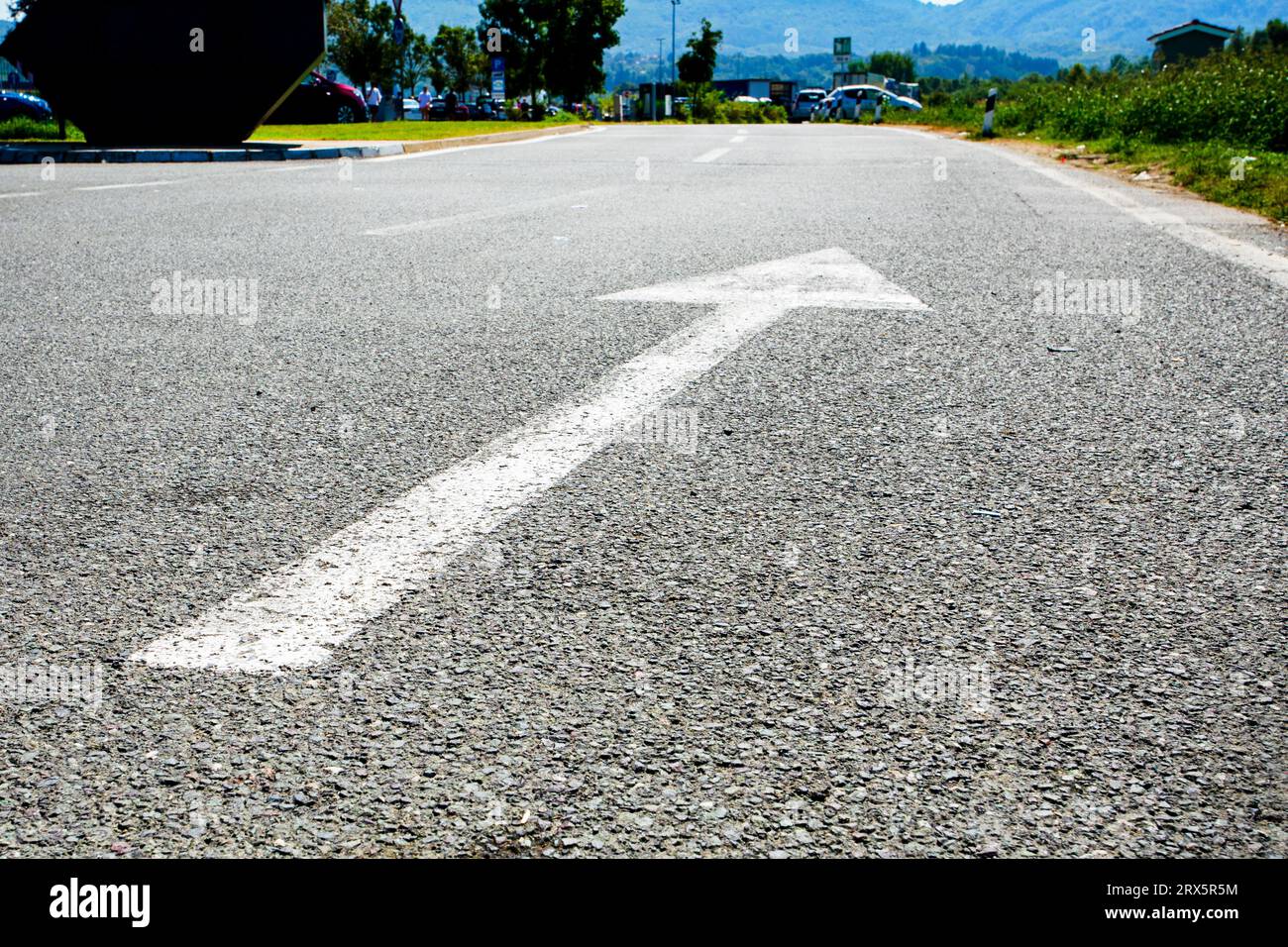 road white arrow sign on the road in the mountains before gas stations ...