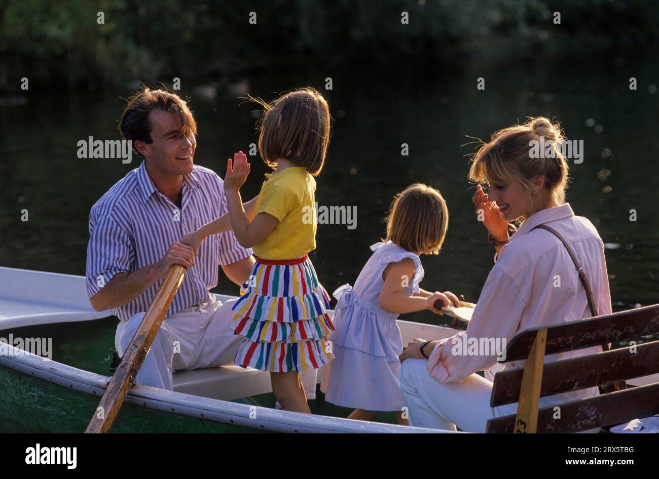 Young family with 2 two children in a rowing boat, girl, parents ...