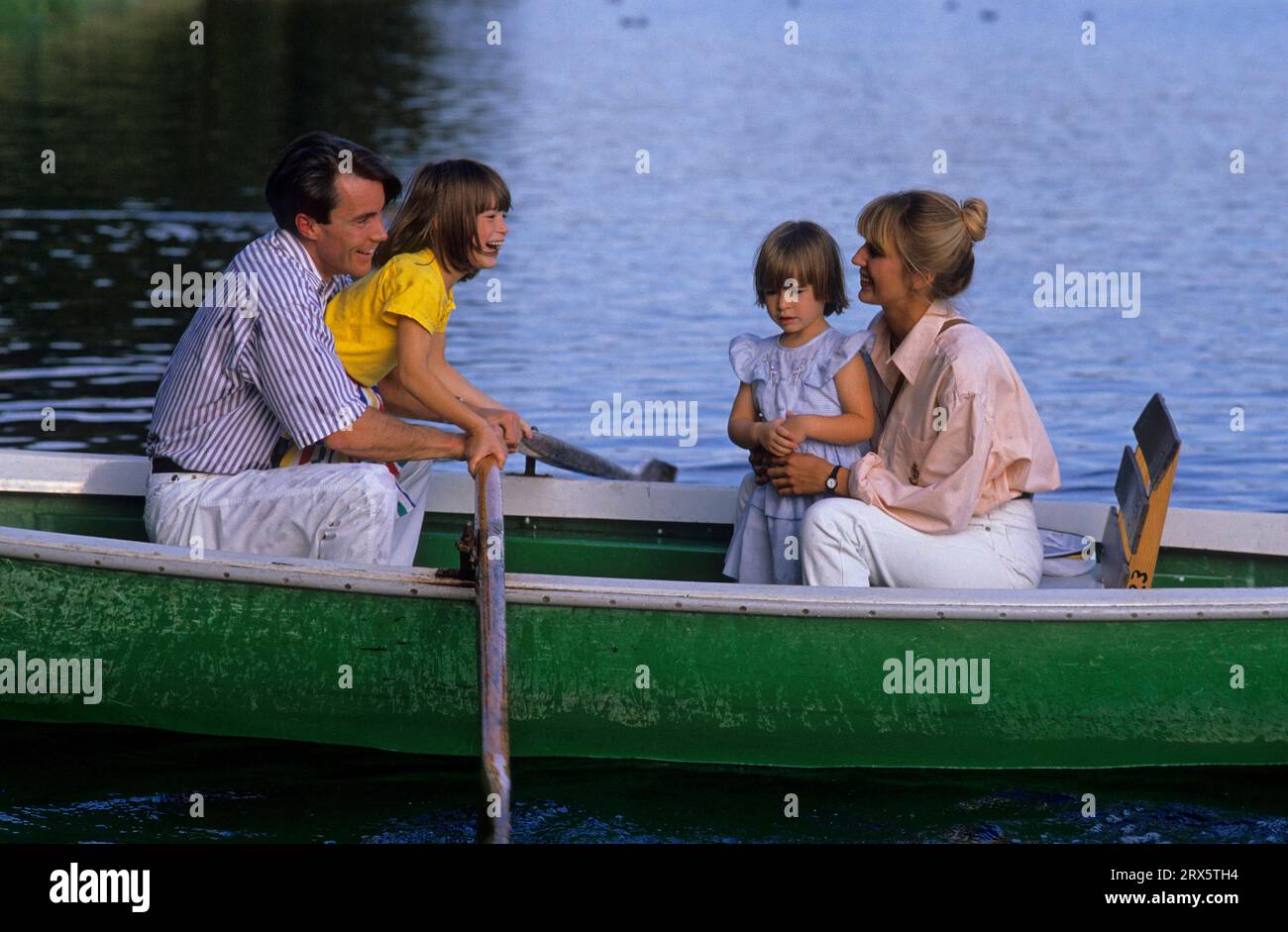 Young family with 2 two children in a rowing boat, girl, parents ...