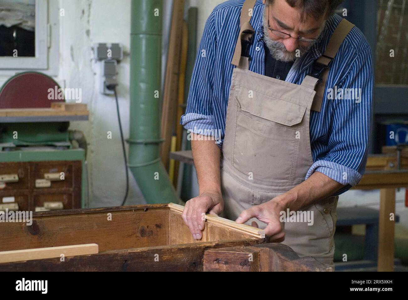 A furniture restorer (carpenter) restores a baroque chest of drawers ...
