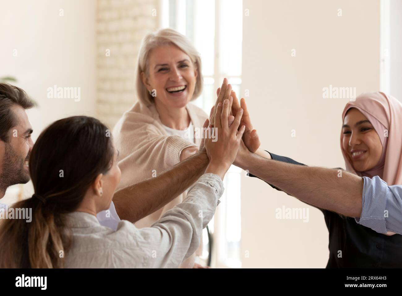 Diverse staff celebrating sales growth giving high five showing unity ...