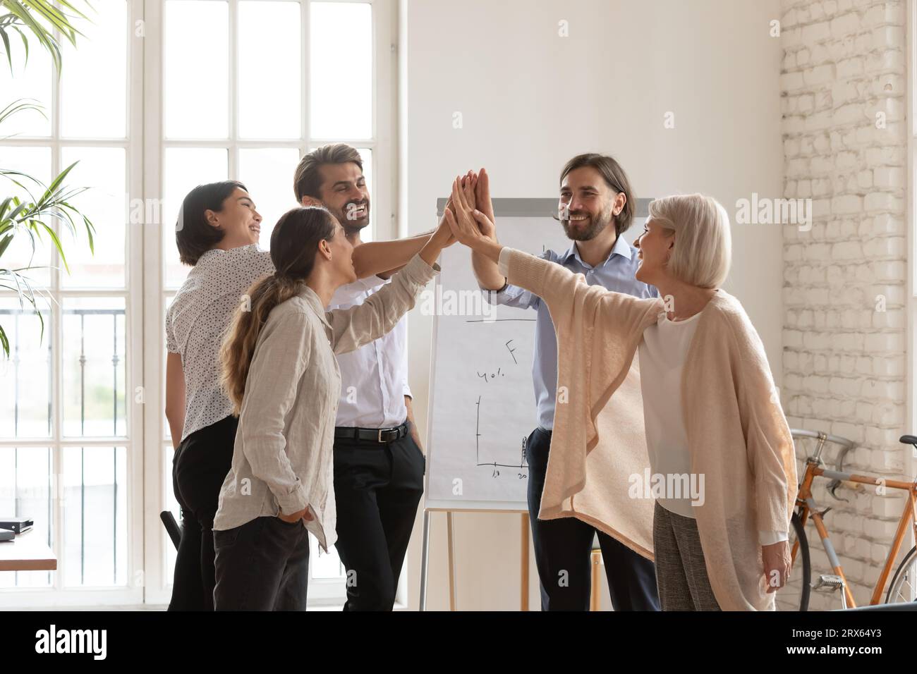 Diverse mates celebrating success stack palms together giving high five ...