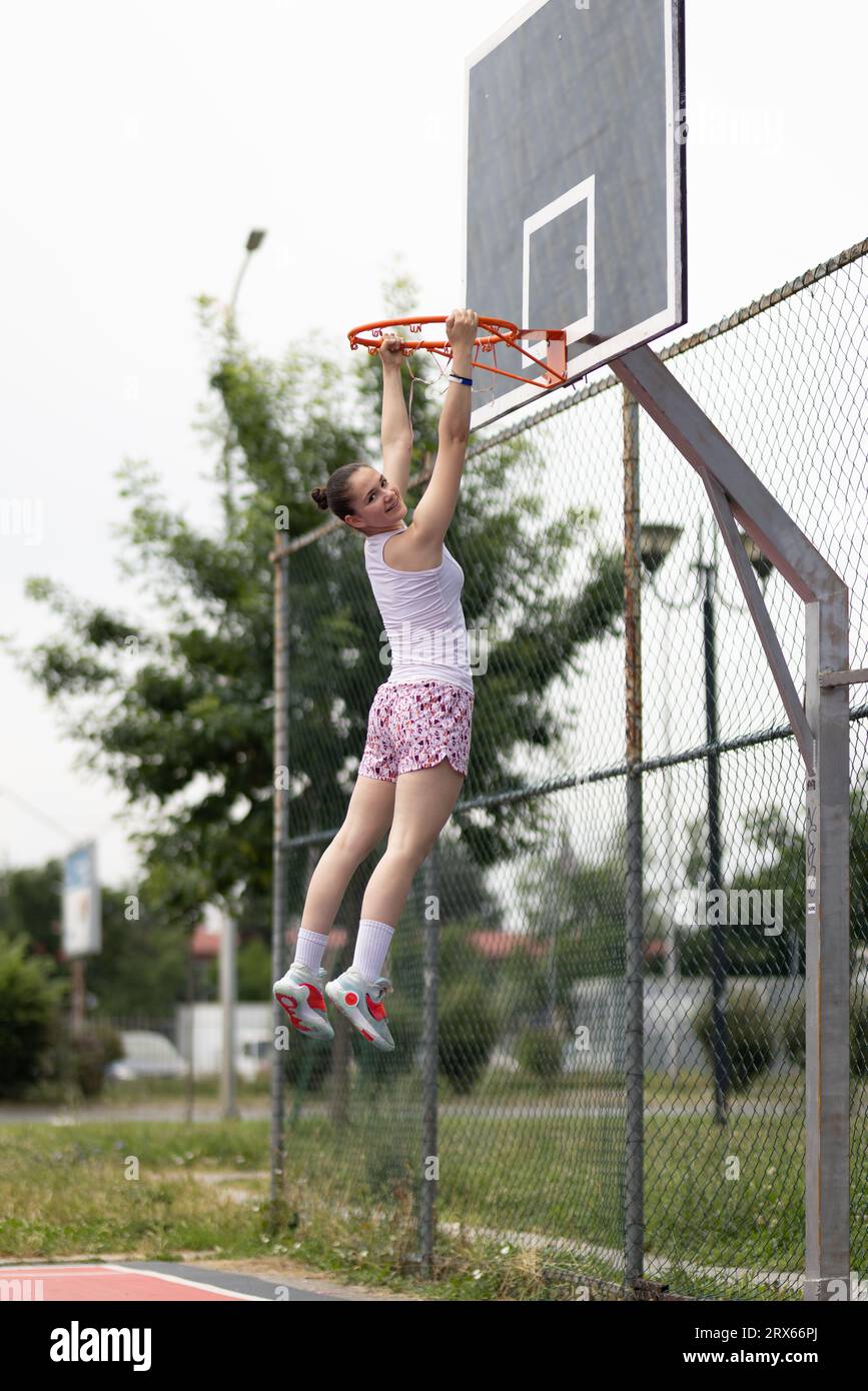 Young girl playing basketball. Hanging on the hoop. Outdoor sports ...
