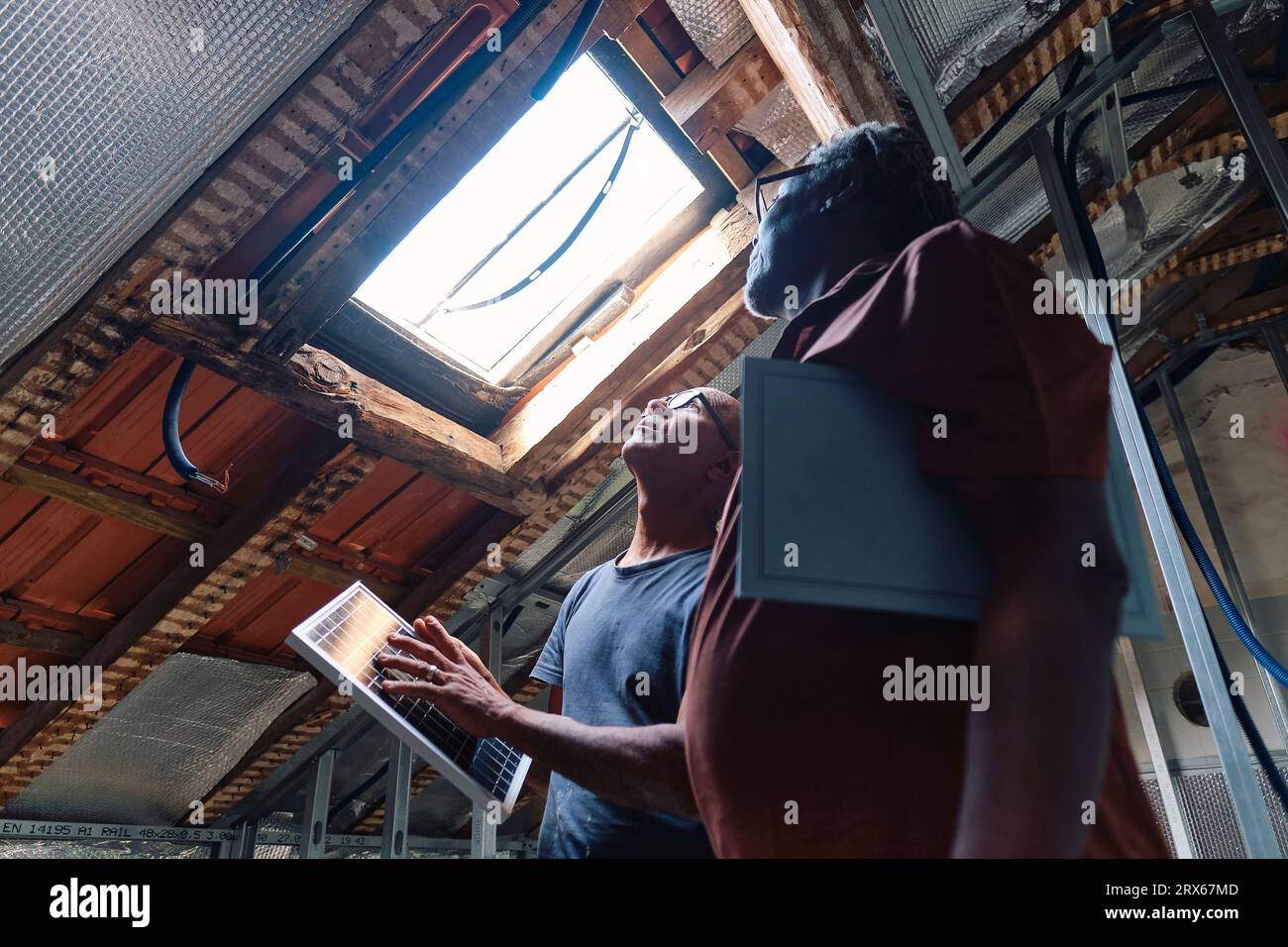 Architect and builder holding solar panel and looking through ceiling ...