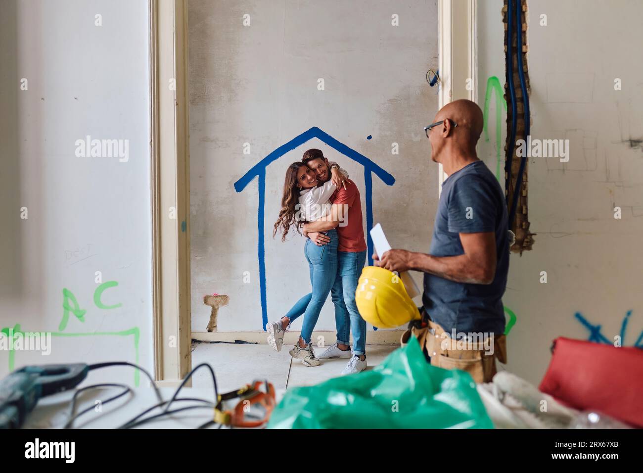 Construction worker with cheerful couple hugging at site Stock Photo ...