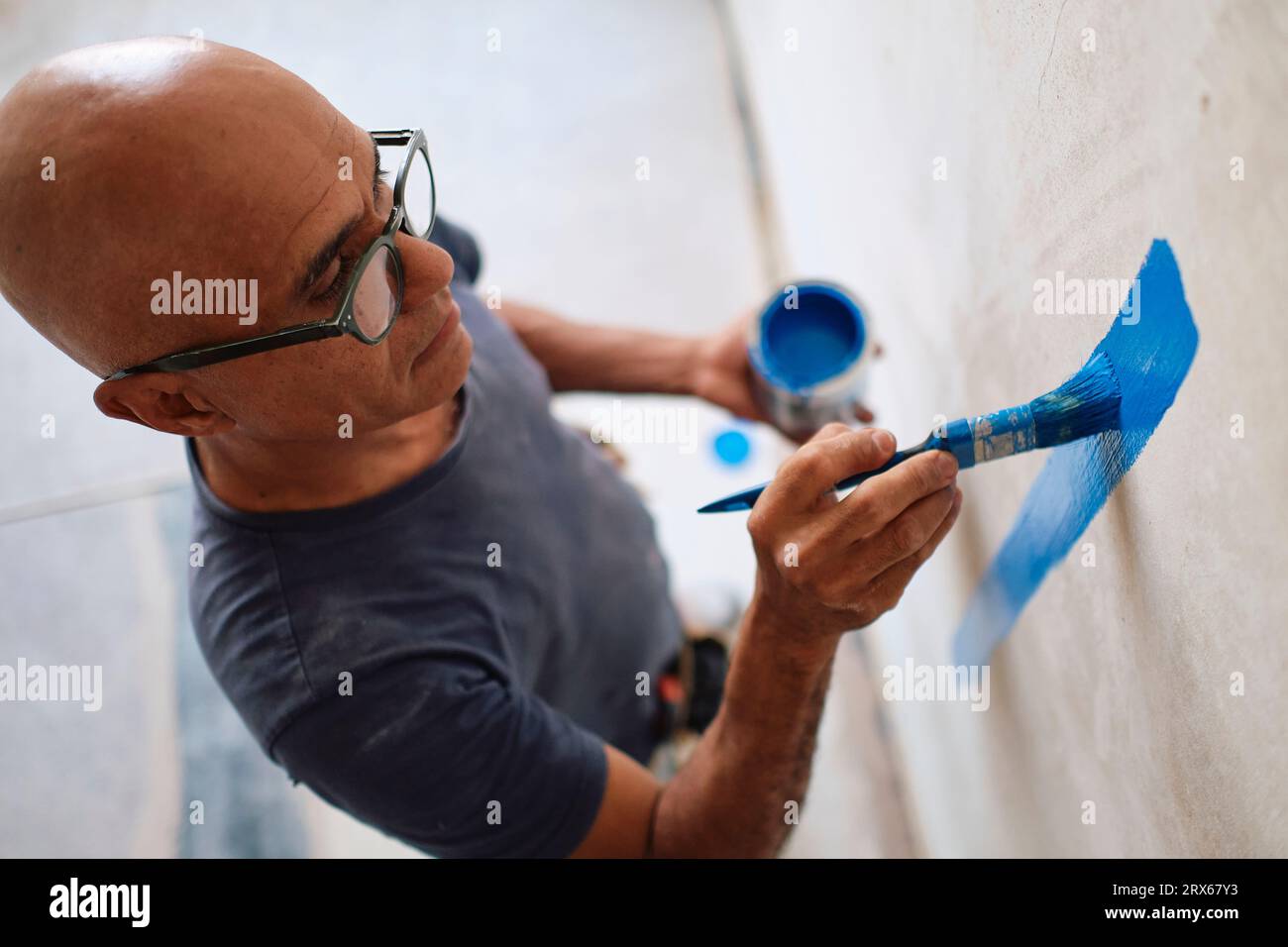 Construction worker painting wall with brush at site Stock Photo - Alamy