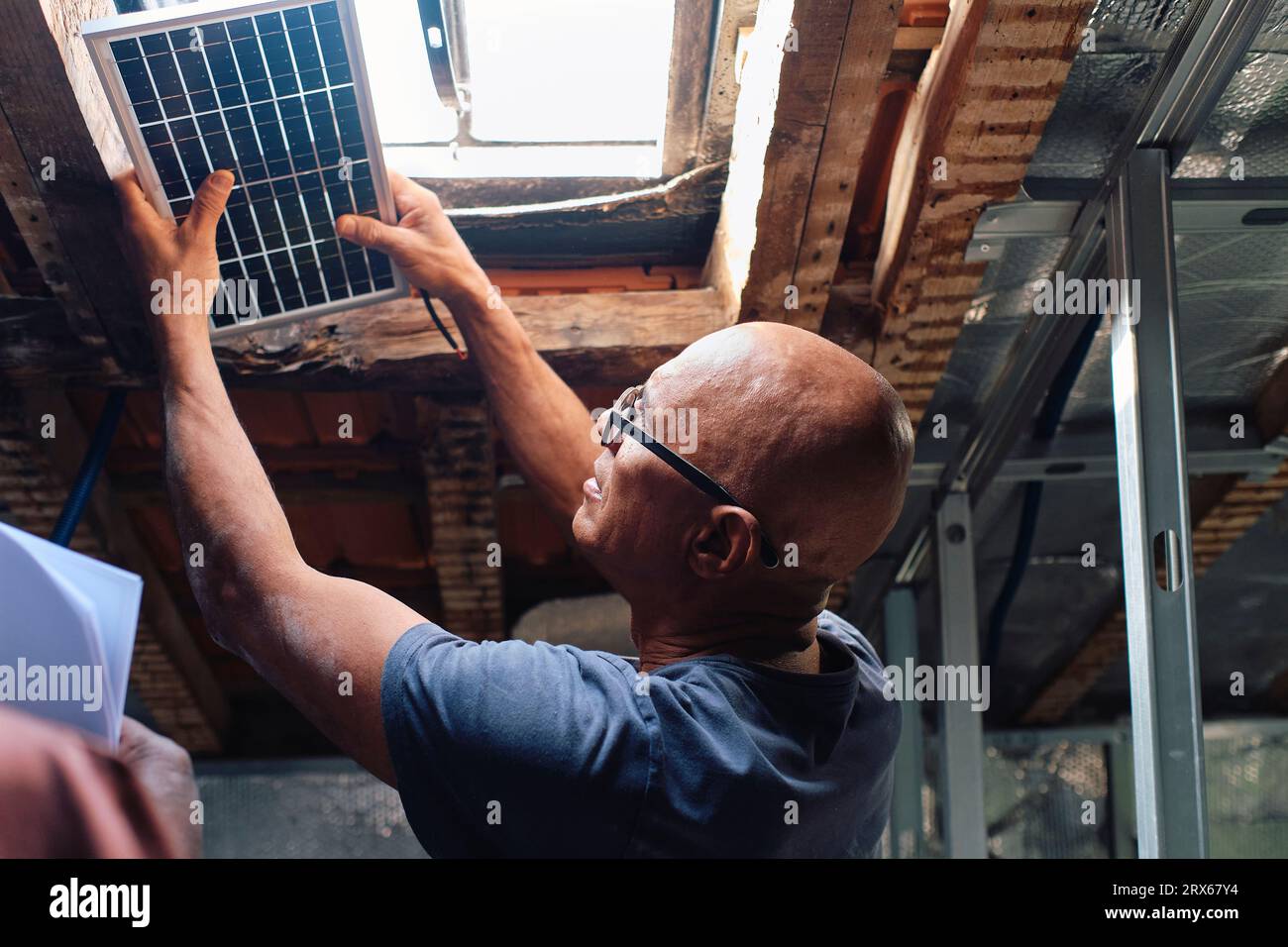Construction worker examining solar panel over window in attic Stock ...