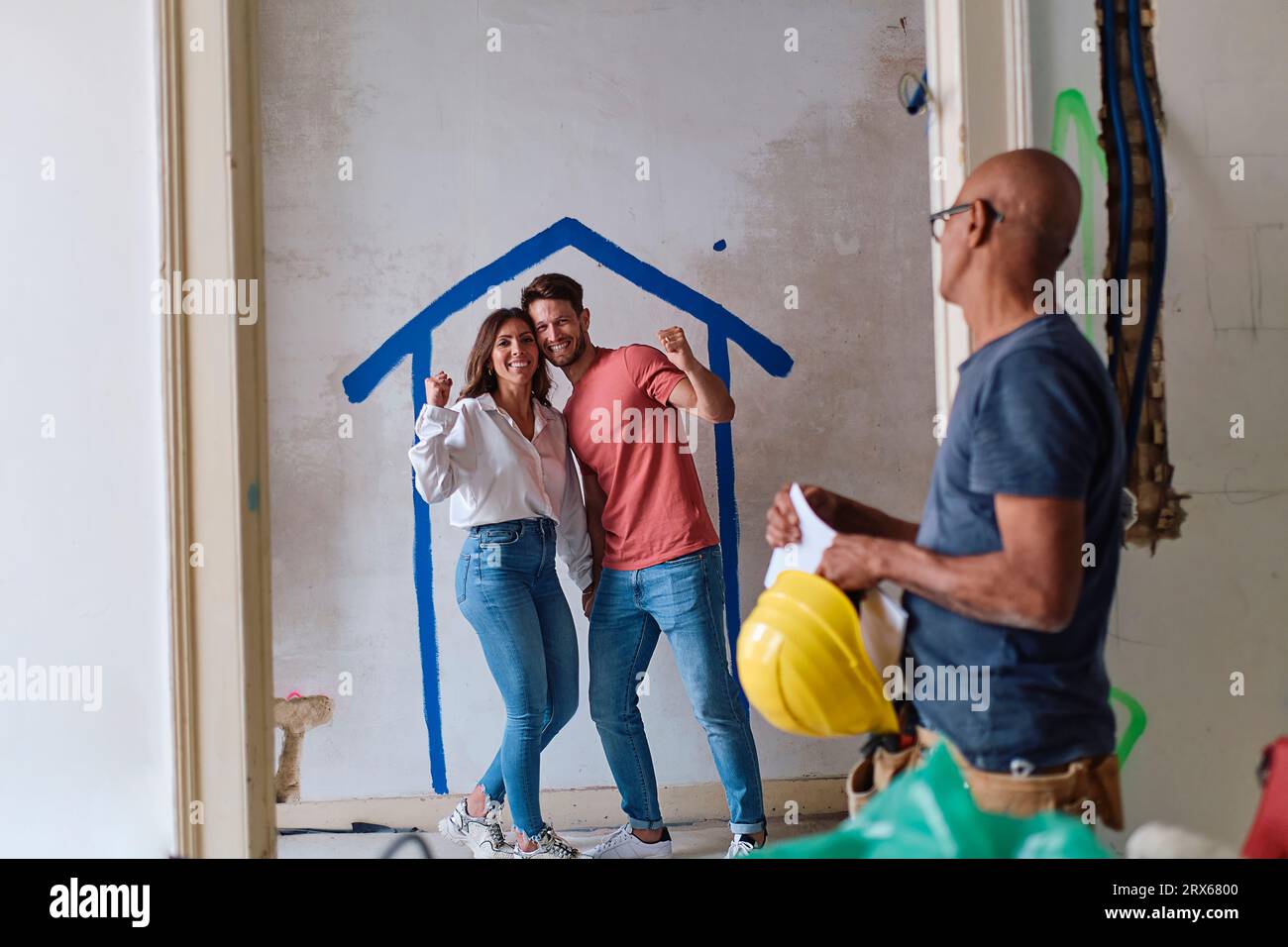 Construction worker with couple cheering in front of wall at site Stock ...
