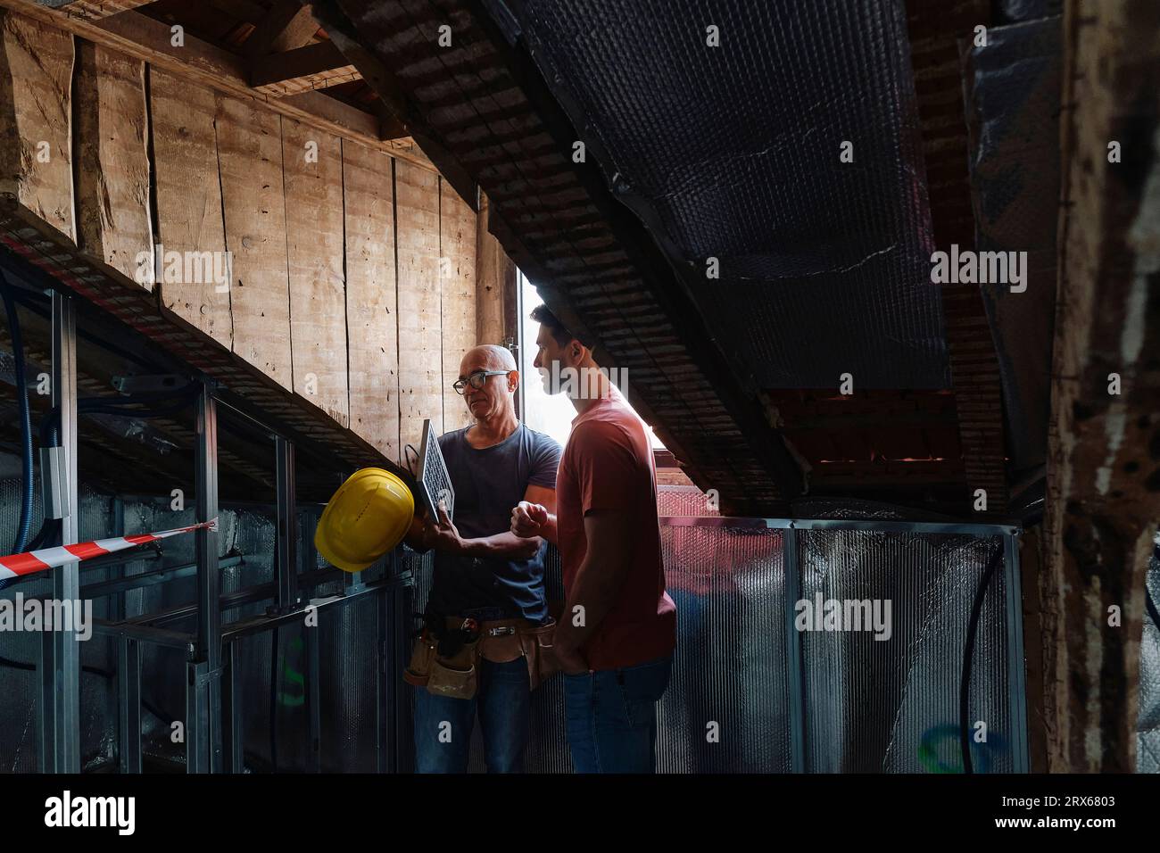 Construction worker holding solar panel and discussing with man in ...
