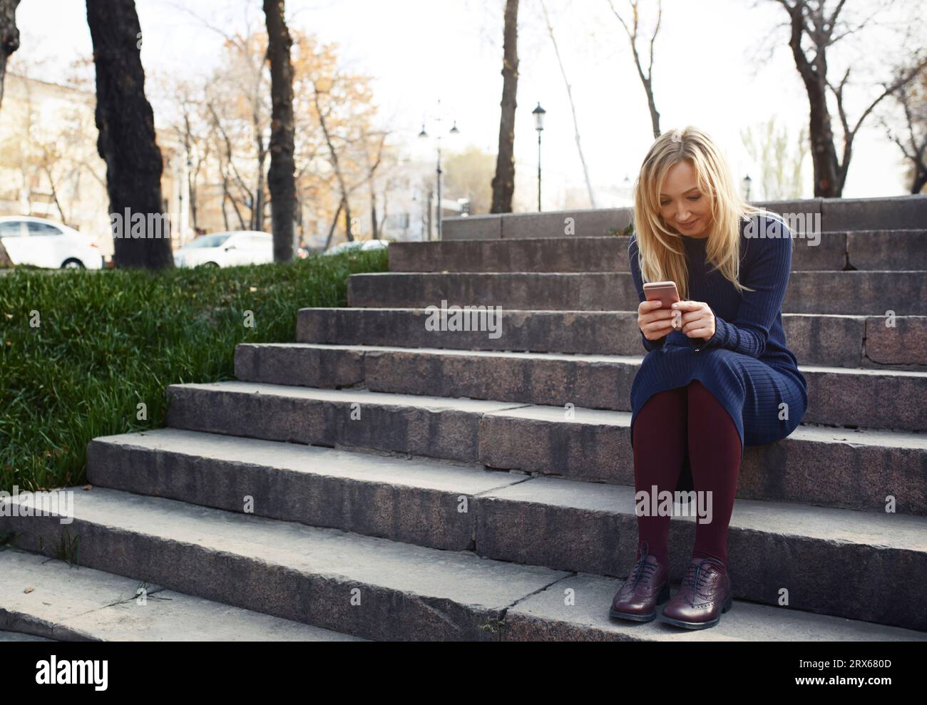 Blond woman using mobile phone sitting on steps Stock Photo - Alamy