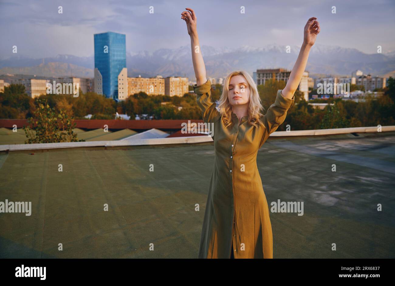 Carefree young woman with arms raised dancing on rooftop Stock Photo ...