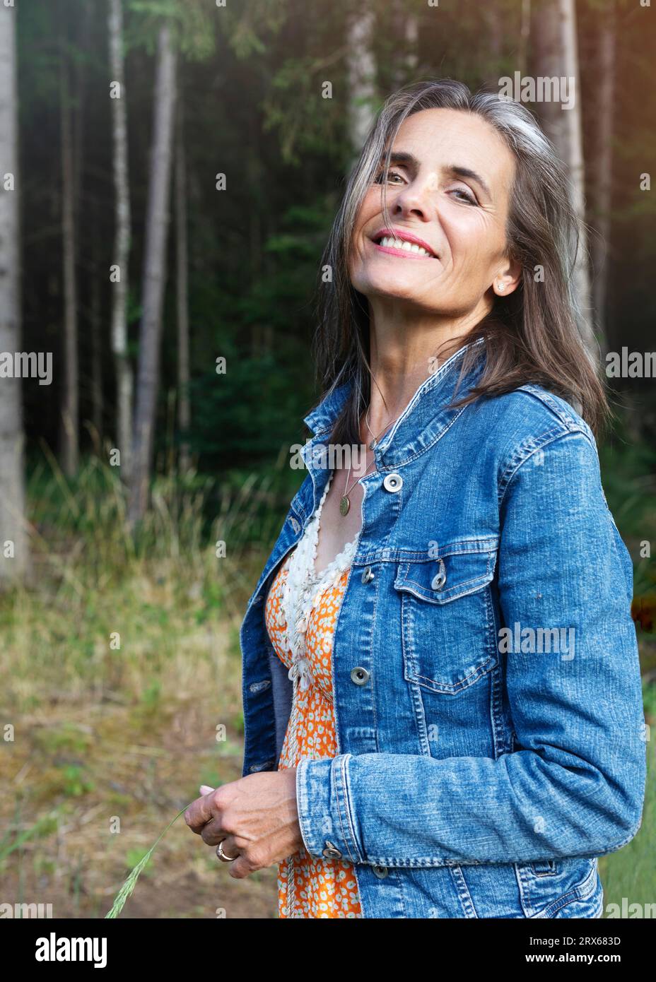 Smiling mature woman in denim jacket at forest Stock Photo - Alamy