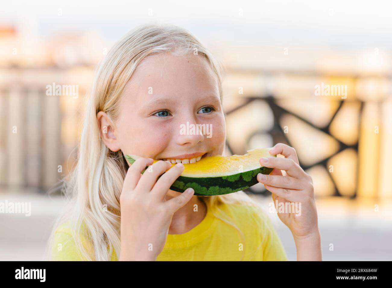 Smiling blond girl eating yellow watermelon Stock Photo - Alamy