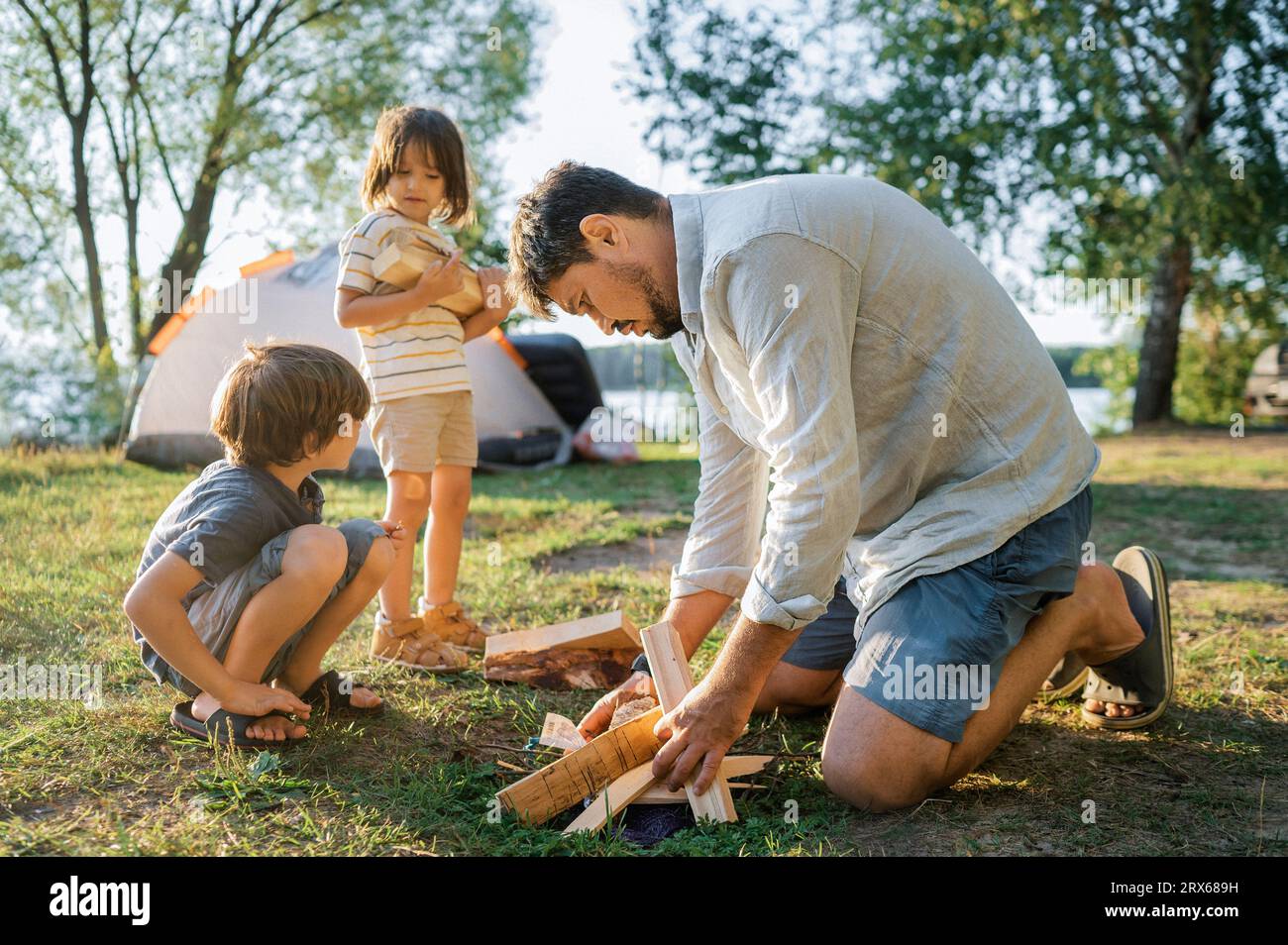 Father and children with wood preparing for bonfire on grass Stock ...