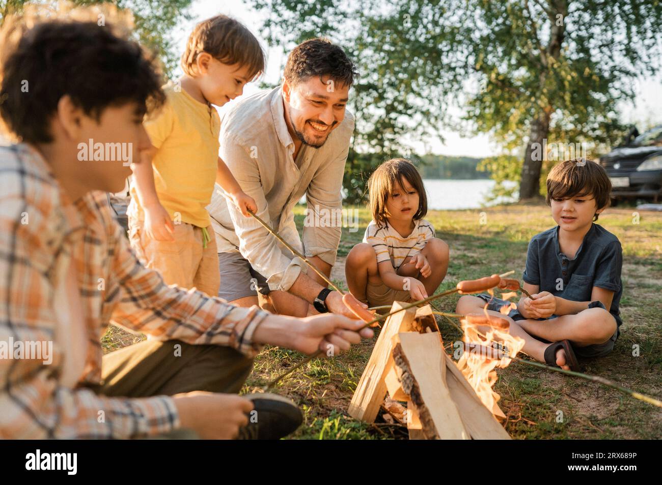 Happy father and children roasting sausages in bonfire Stock Photo - Alamy