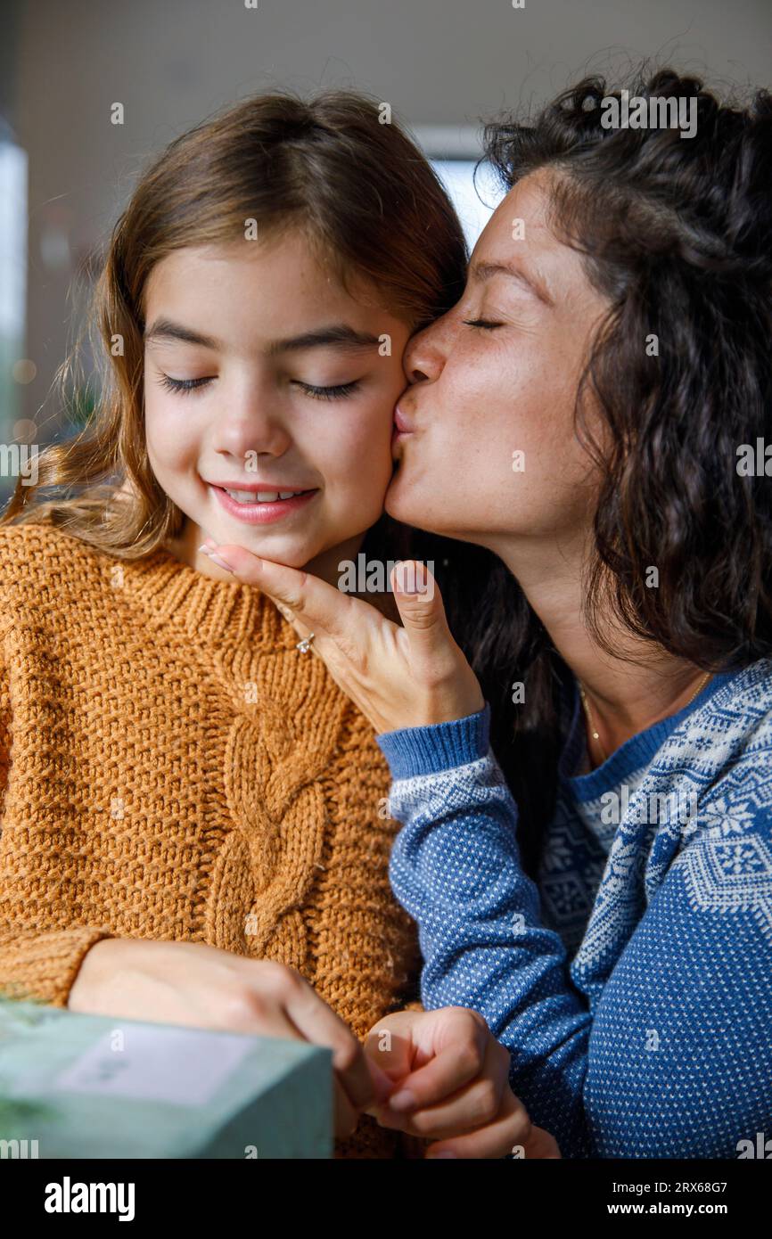 Mother kissing smiling daughter at home Stock Photo - Alamy