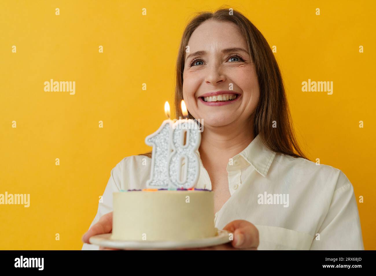 Happy woman holding birthday cake against yellow background Stock Photo ...