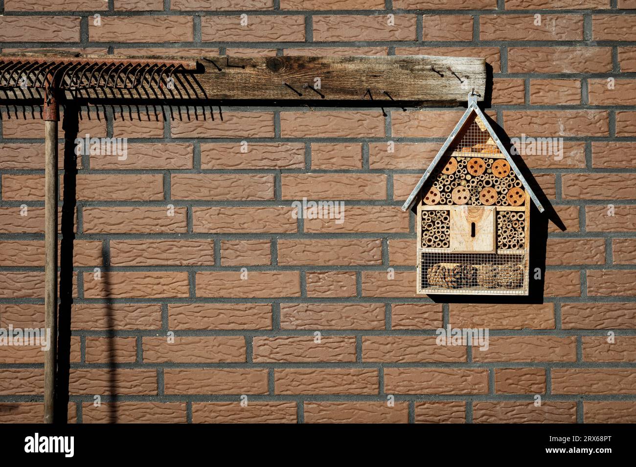 Insect hotel,and rake hanging on brick wall Stock Photo - Alamy