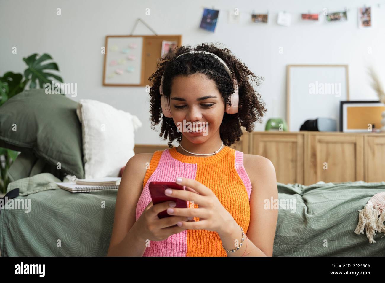 Happy teenage girl using mobile phone in bedroom Stock Photo - Alamy