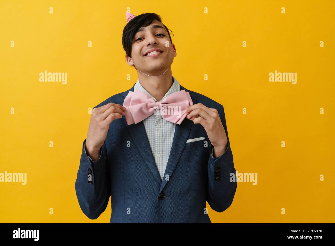 Smiling young man wearing bow tie against yellow background Stock Photo ...