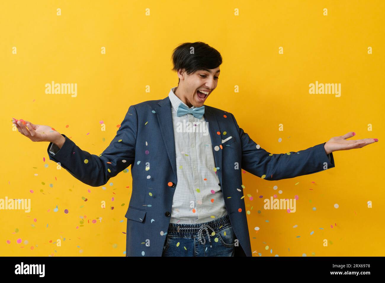 Cheerful man celebrating with confetti against yellow background Stock ...