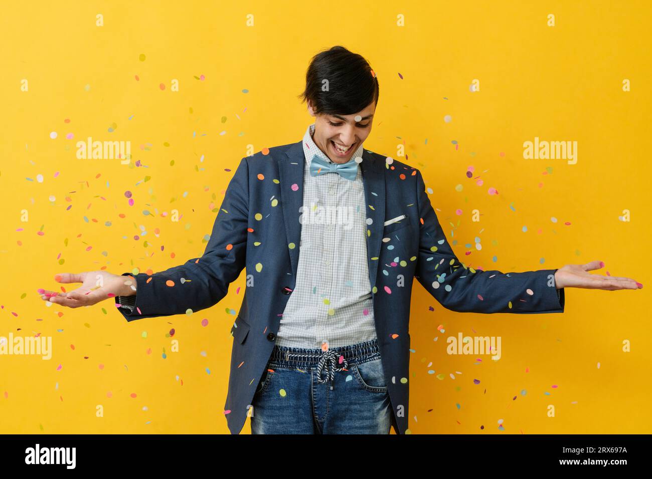Happy man playing with confetti against yellow background Stock Photo ...