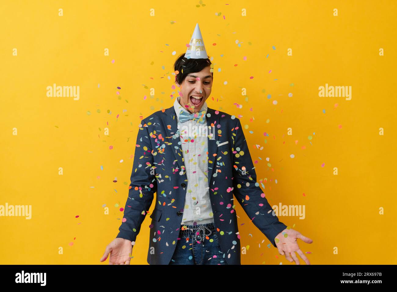 Cheerful man enjoying with confetti against yellow background Stock ...