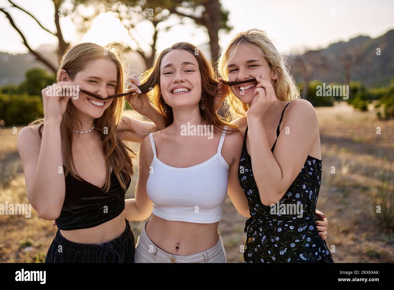 Smiling women making mustache from friend's hair in park Stock Photo - Alamy