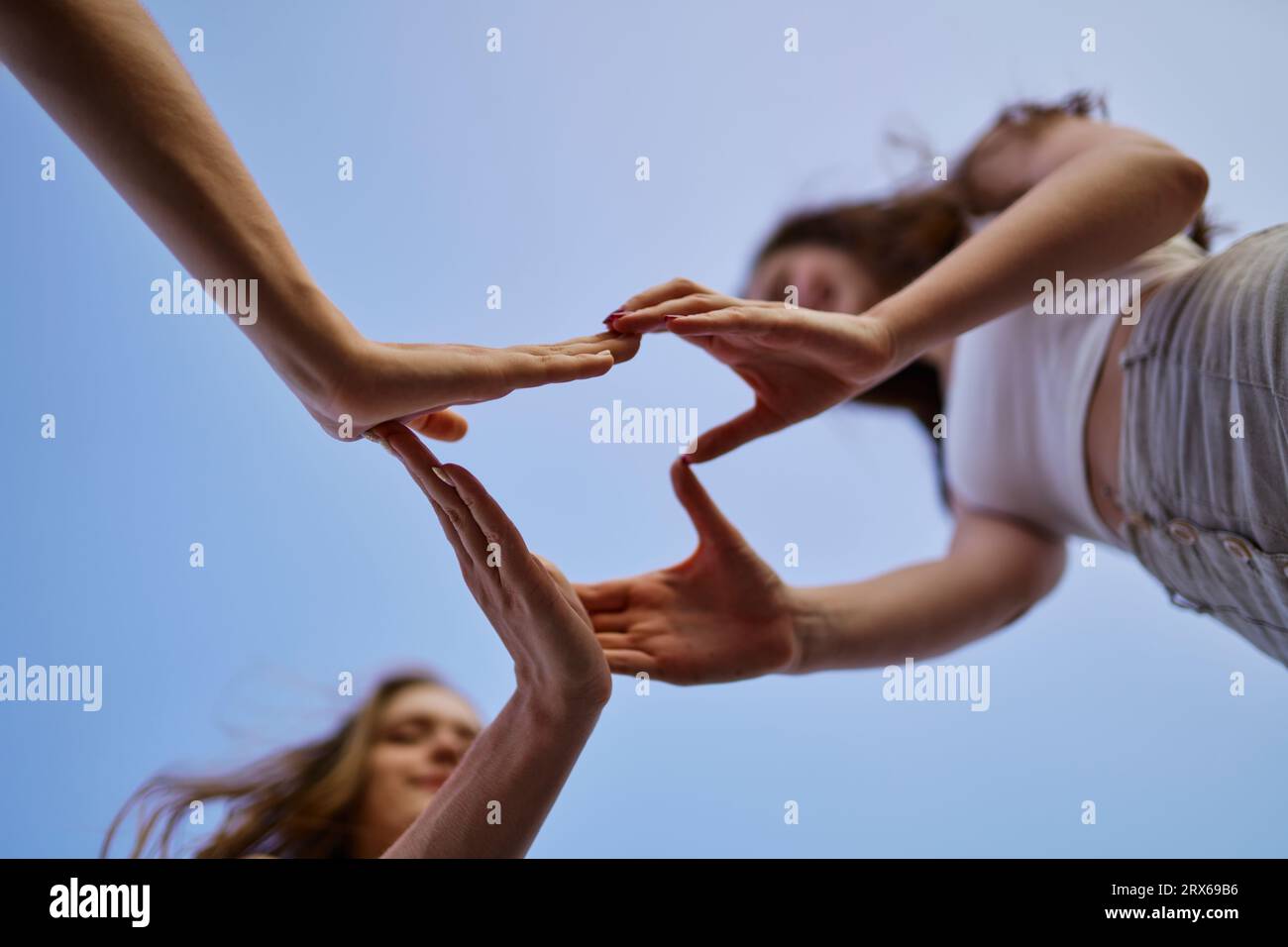 Friends gesturing heart shape with hands under clear sky Stock Photo ...
