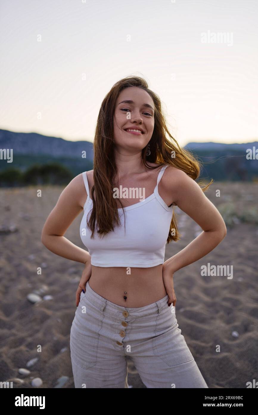 Happy woman with hands on hips standing at beach Stock Photo - Alamy