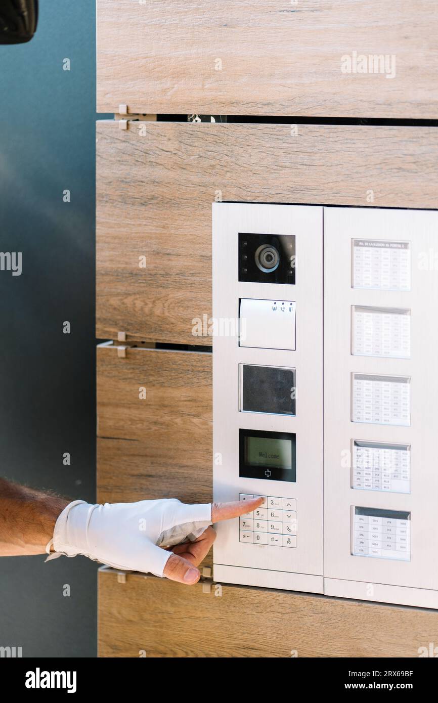 Hand of delivery person entering password on door combination lock ...