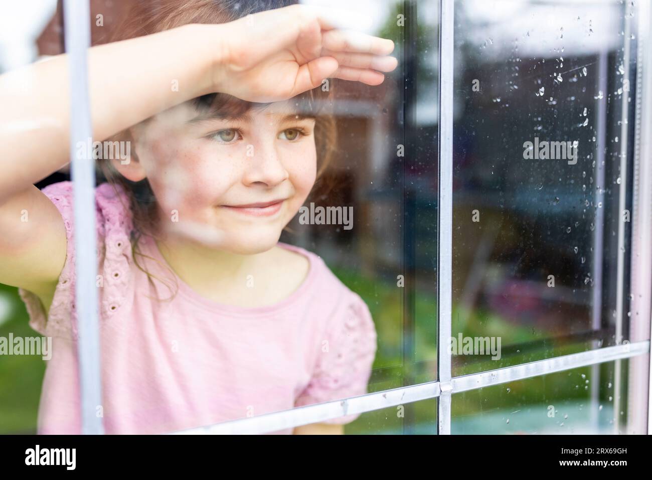 Innocent girl looking through window Stock Photo - Alamy