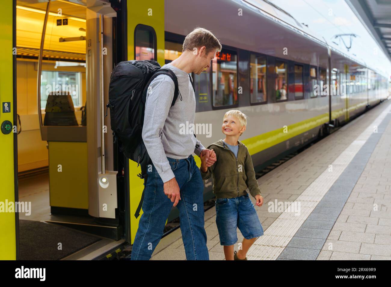 Happy son and father walking on platform in front of train Stock Photo ...