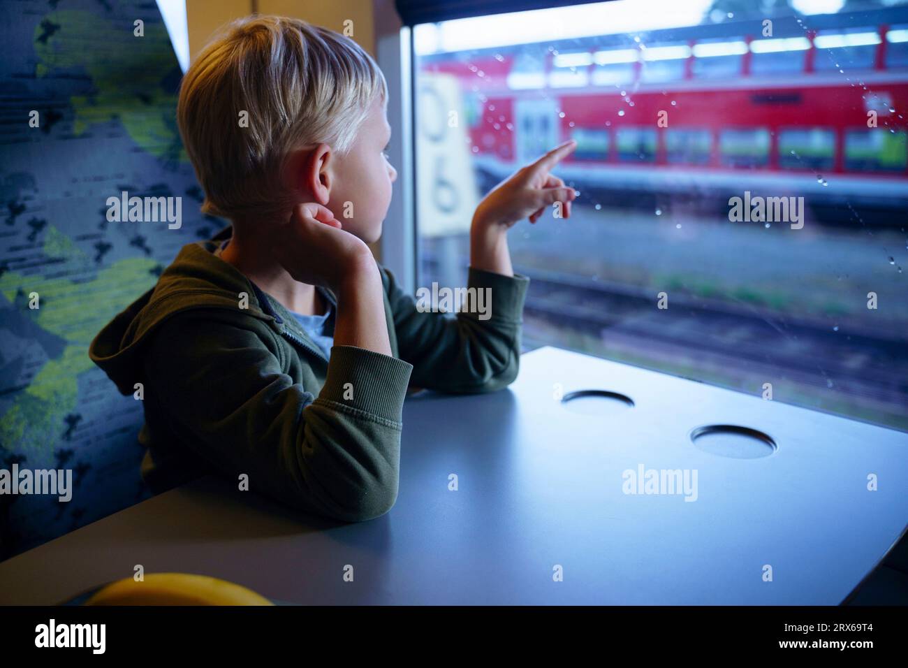 Boy touching glass window sitting in train Stock Photo - Alamy