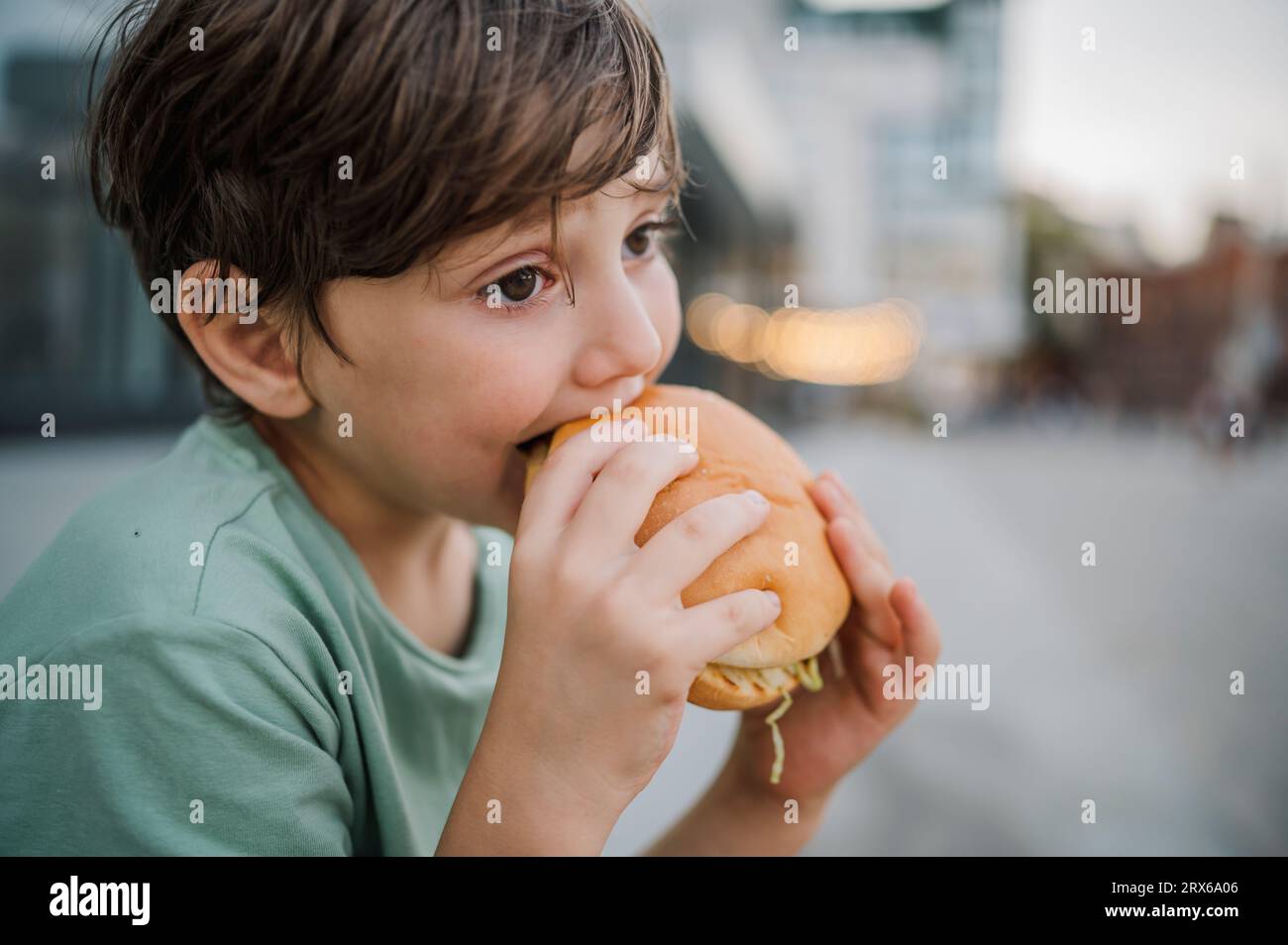 Thoughtful boy eating burger at street Stock Photo - Alamy