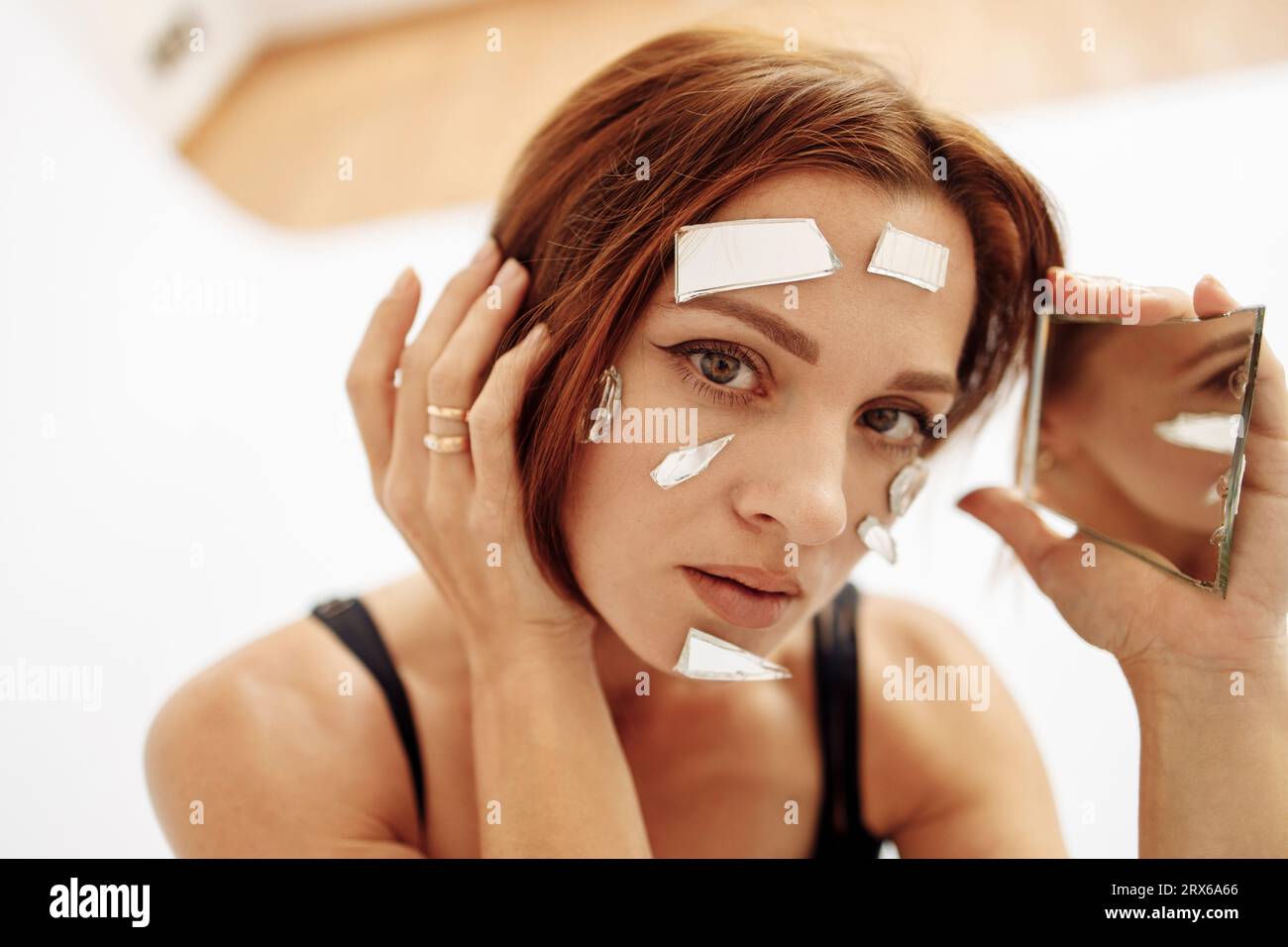 Stressed woman with mirror pieces on face at home Stock Photo - Alamy