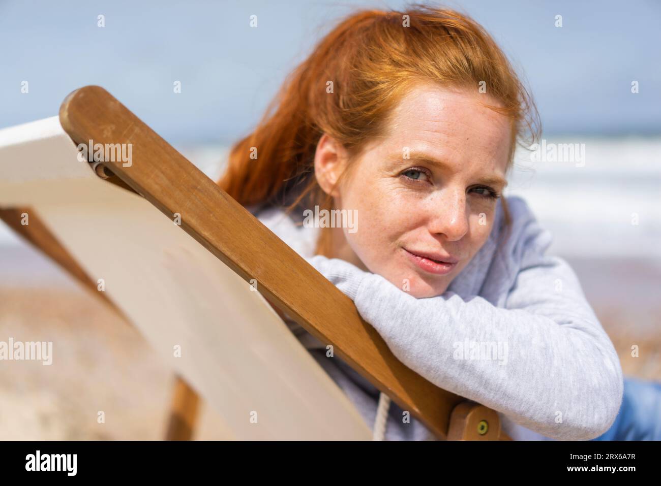 Redhead woman on deck chair at beach holiday Stock Photo - Alamy