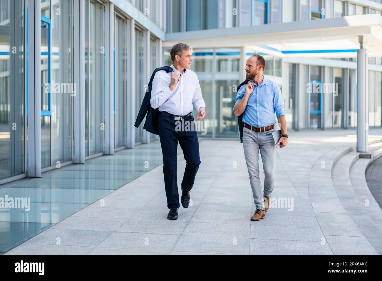 Two managers walking in modern building talking business Stock Photo ...