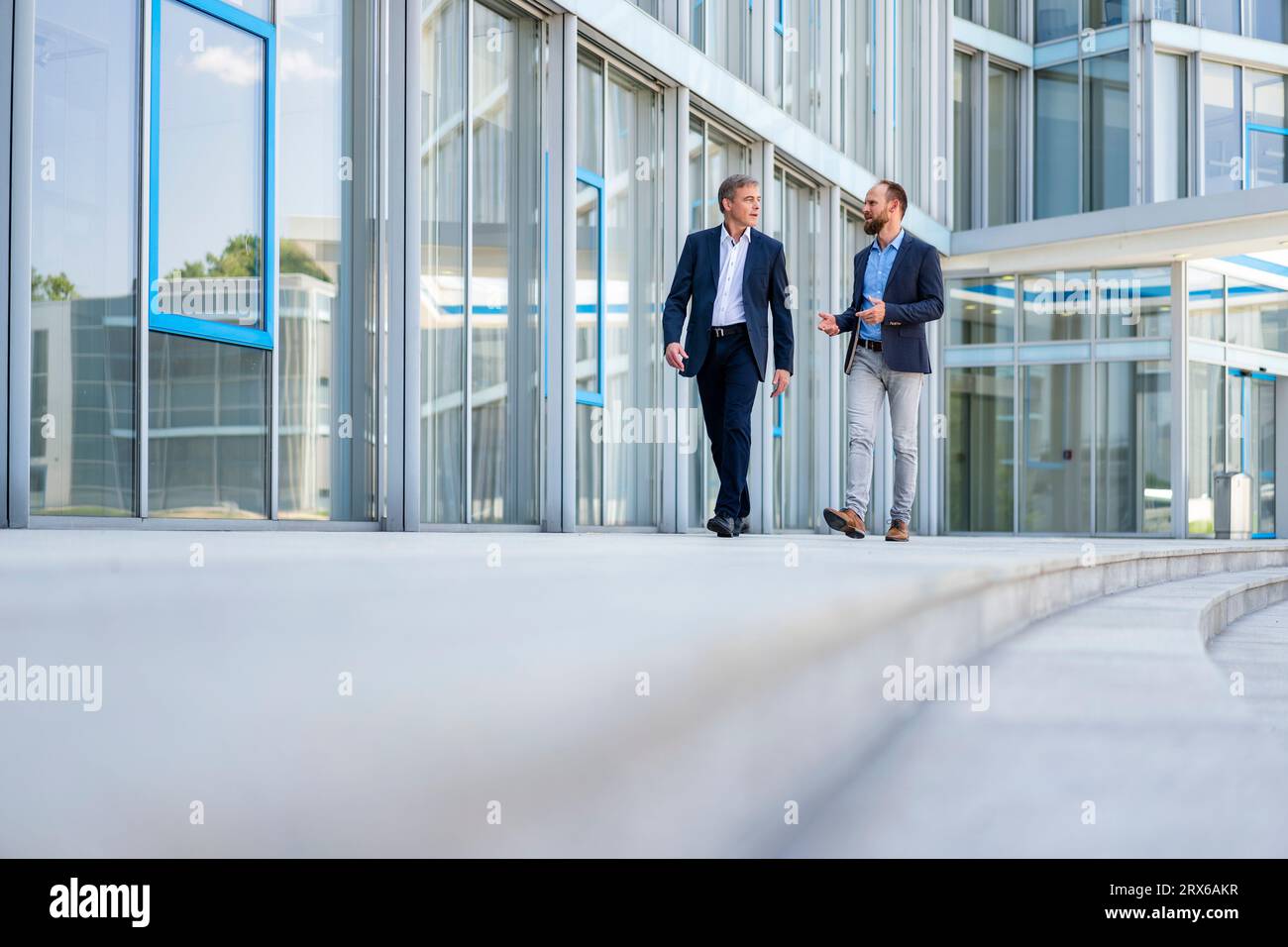 Two managers walking in modern building talking business Stock Photo ...