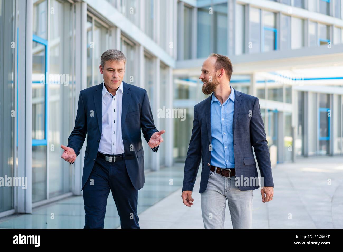 Two managers walking in modern building talking business Stock Photo ...