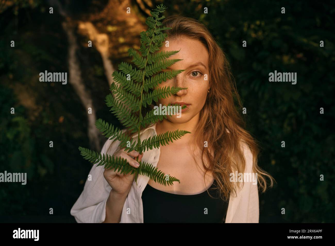 Young blond woman covering face with fern stem Stock Photo - Alamy
