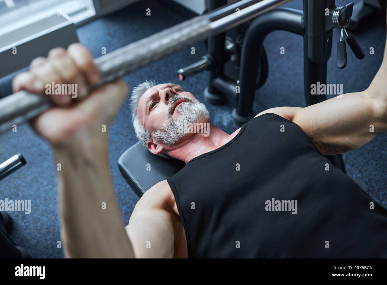 Mature man doing bench press in health club Stock Photo - Alamy