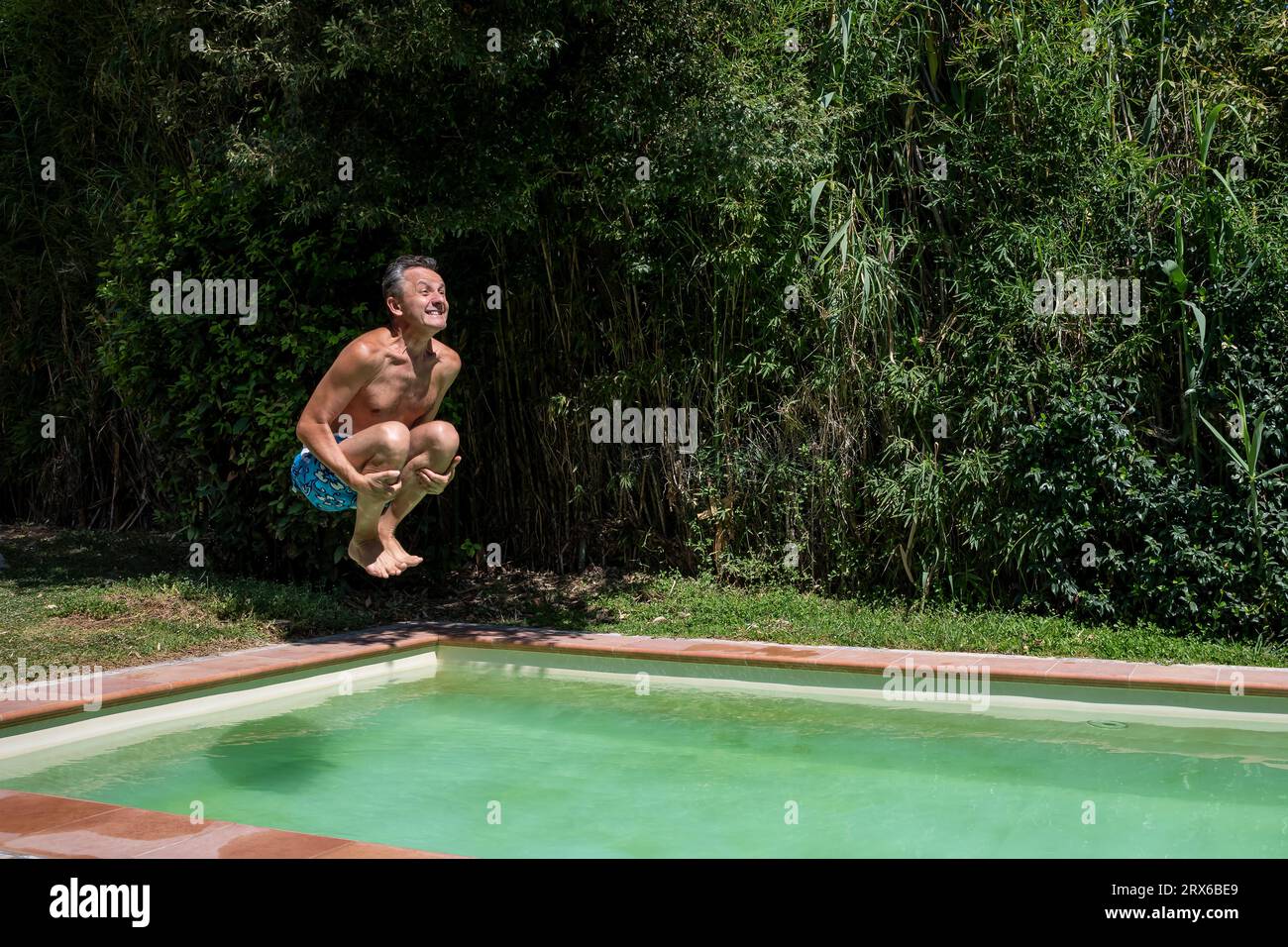 A middle-aged man dives into the pool cannonball style, with a funny ...