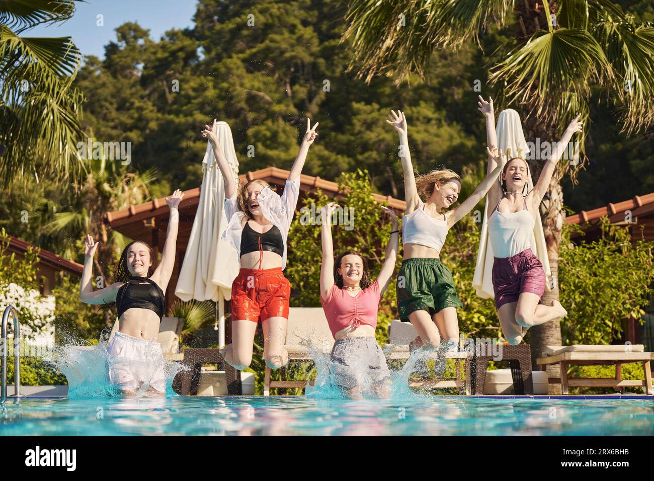 Cheerful friends jumping together into swimming pool Stock Photo - Alamy