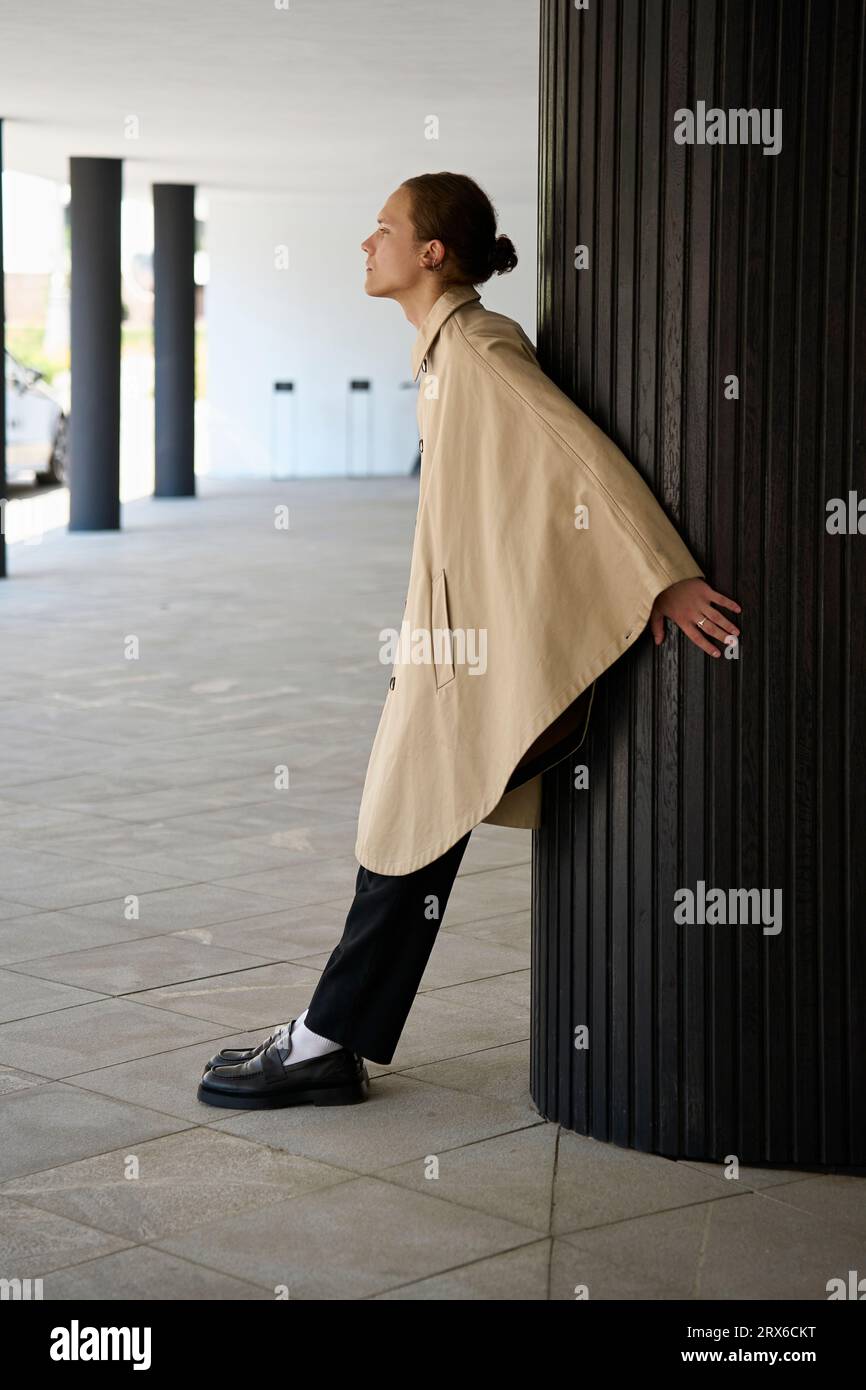 Man wearing poncho leaning on column Stock Photo - Alamy